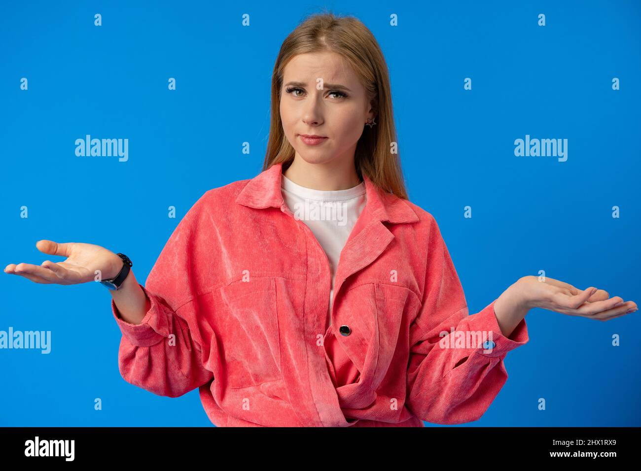 Portrait of a beautiful confused young girl on blue background Stock ...