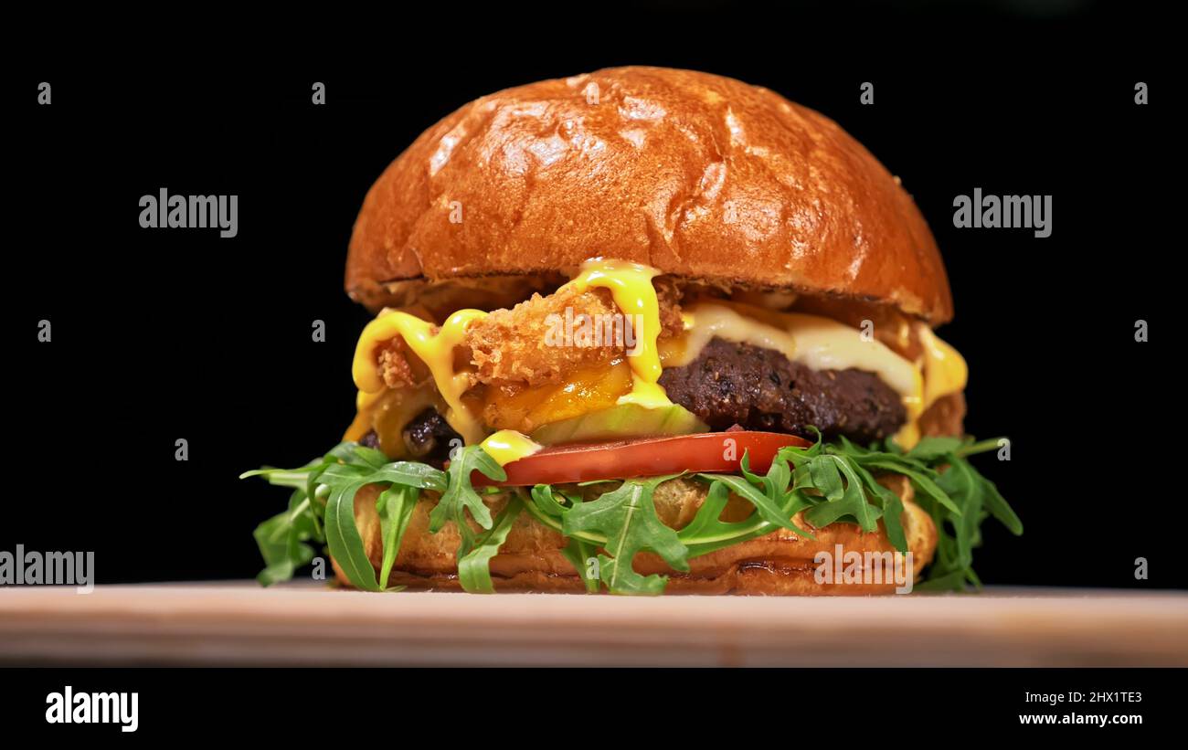 Craft burger is cooking on black background in black food gloves ...