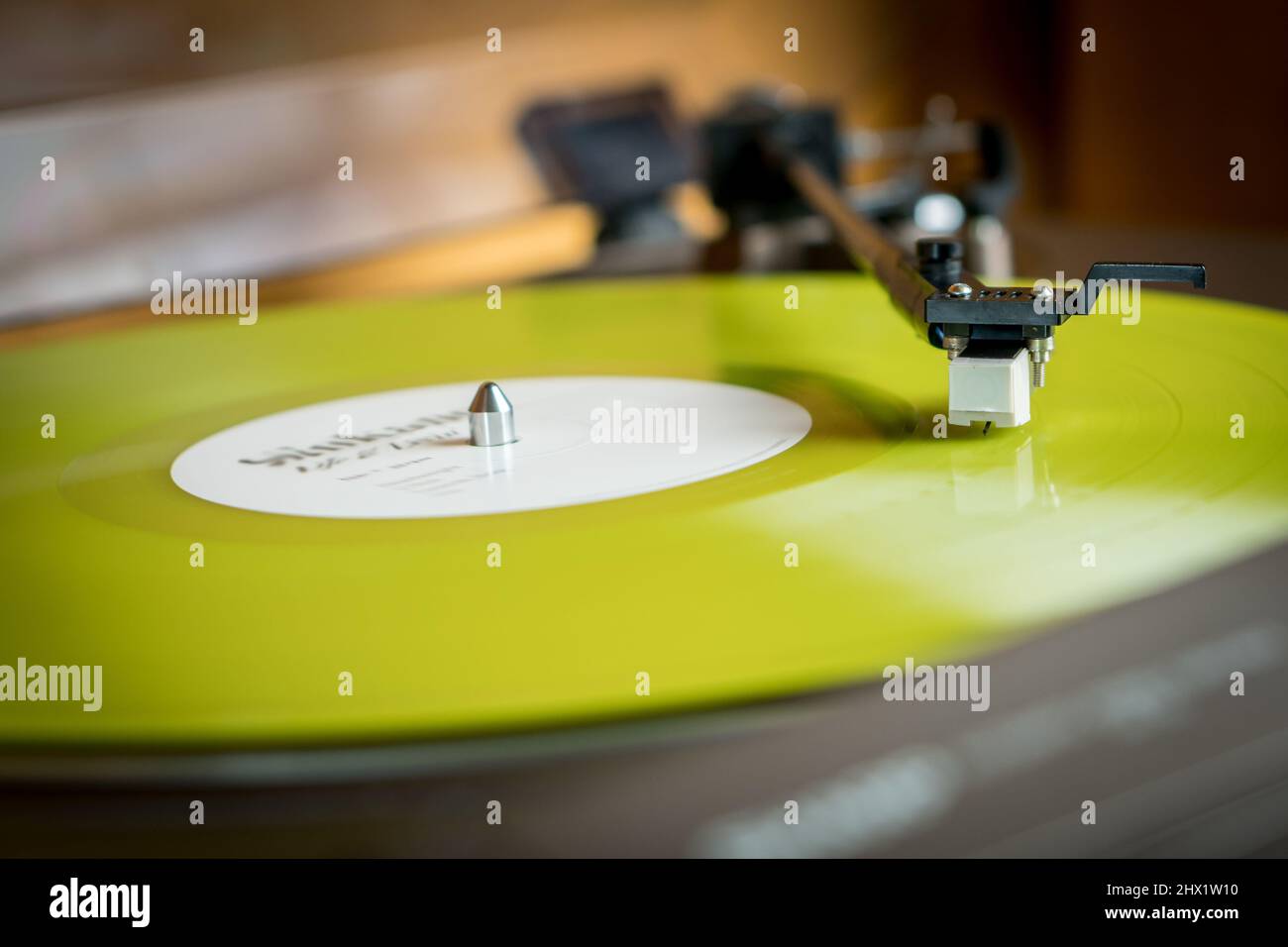 Closeup view of a tonearm and turntable playing color yellow vinyl ...