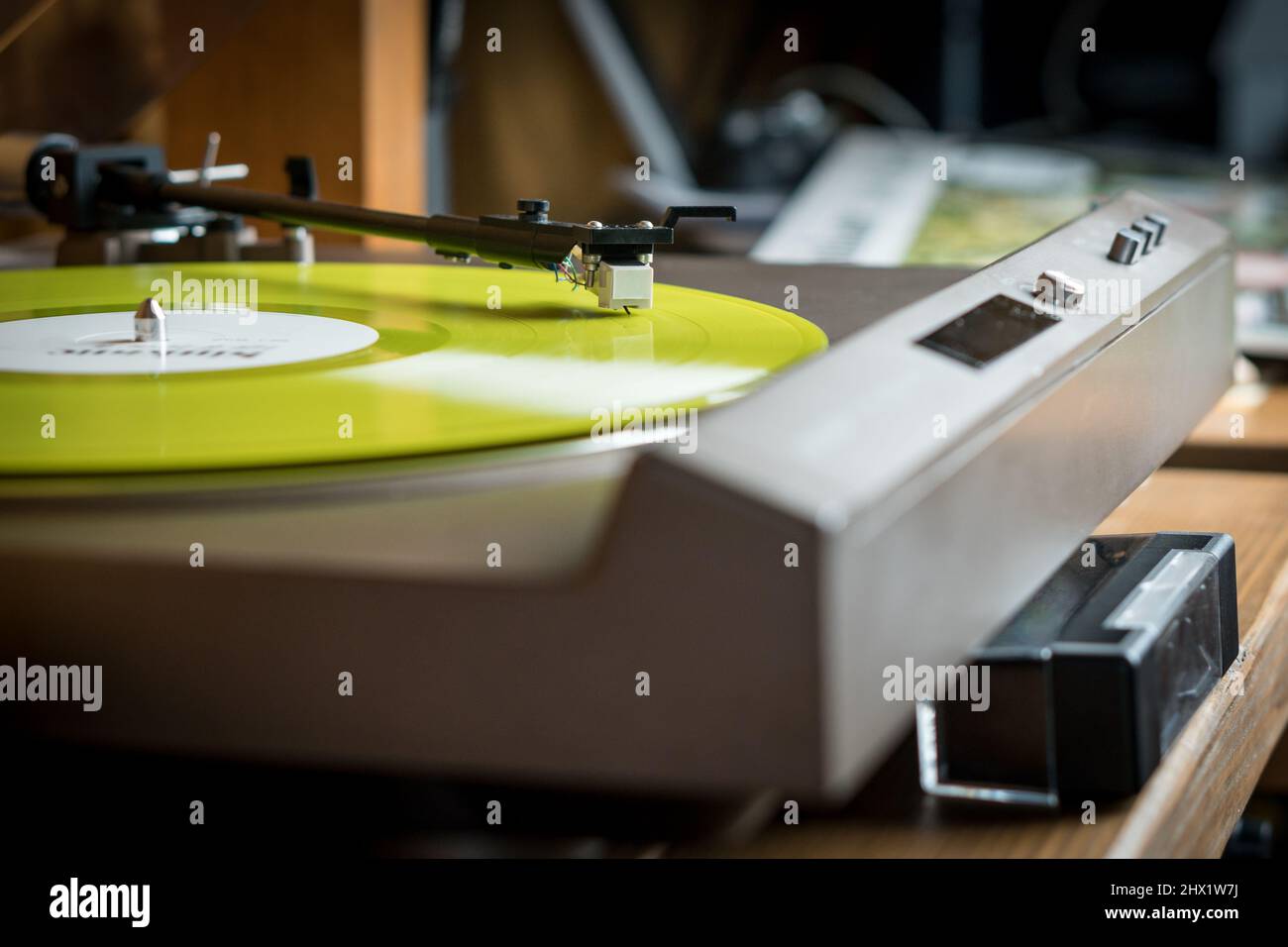 Closeup view of a tonearm and turntable playing color yellow vinyl ...