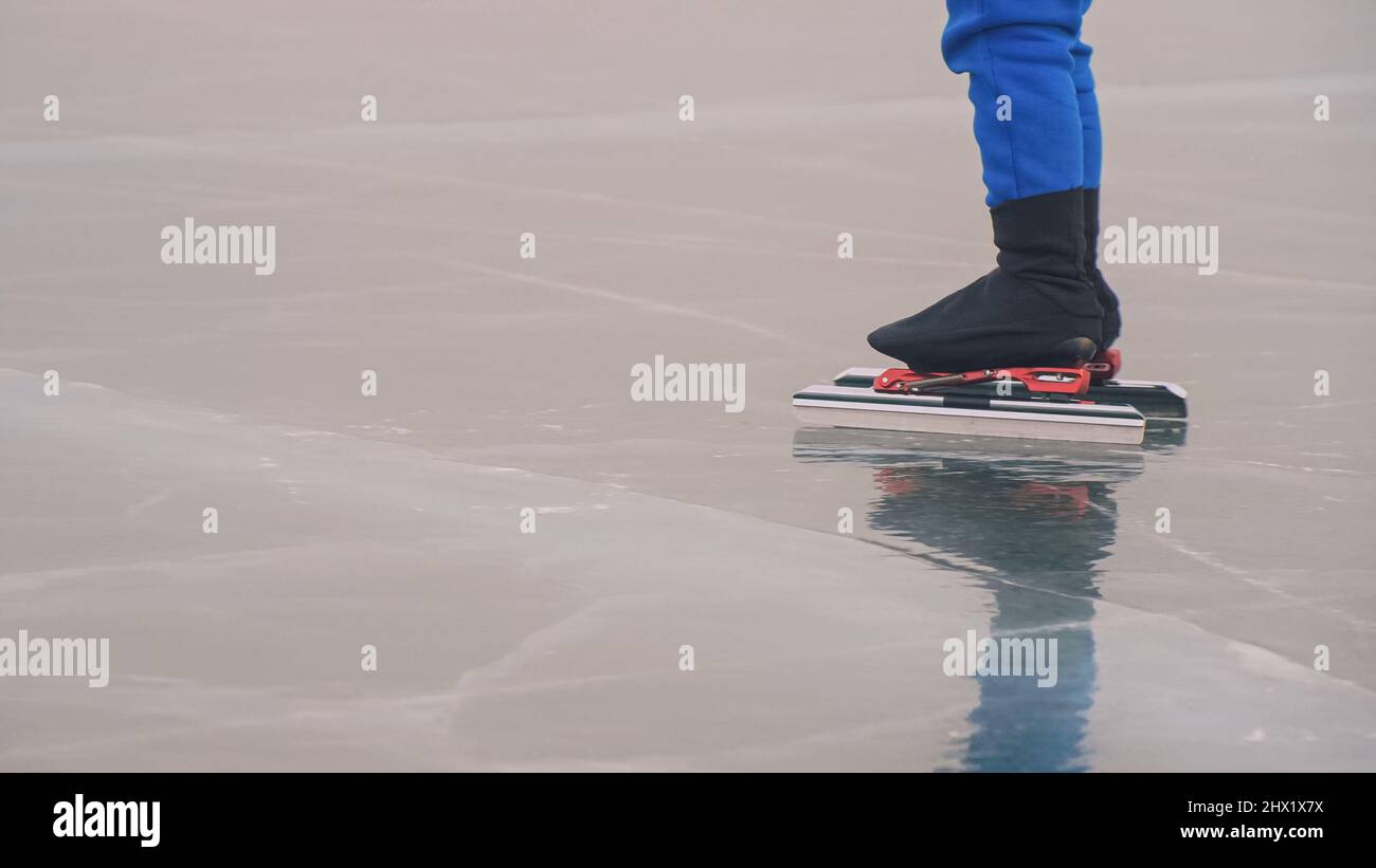 The child train on ice speed skating. The legs in skates close up. The ...