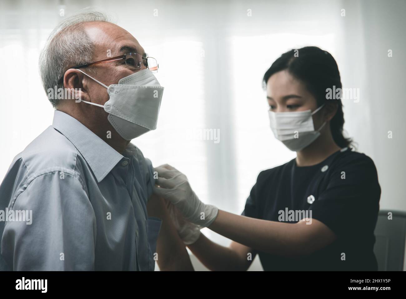 old Asian man vaccinate with doctor woman, giving shot to senior ...