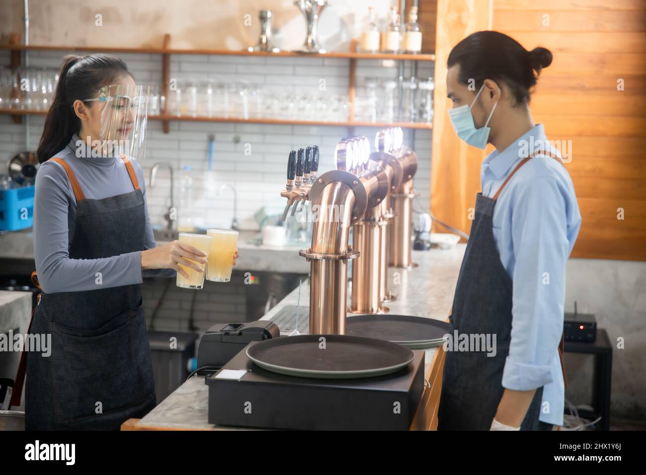 Portrait of Asian bartender girl hand at beer tap pouring , waitress or ...
