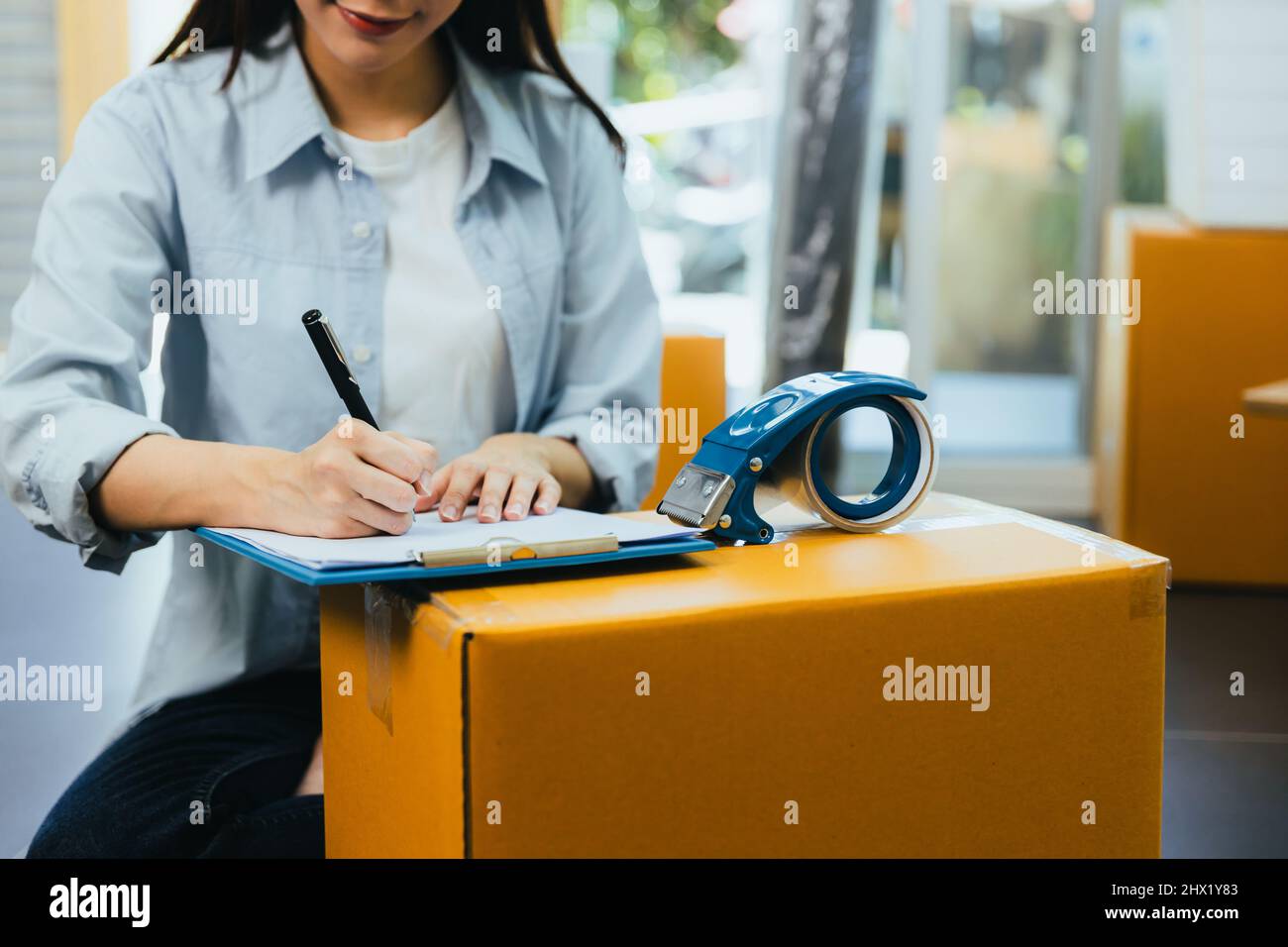 Close up delivery woman, courier checking packing box before sending to ...