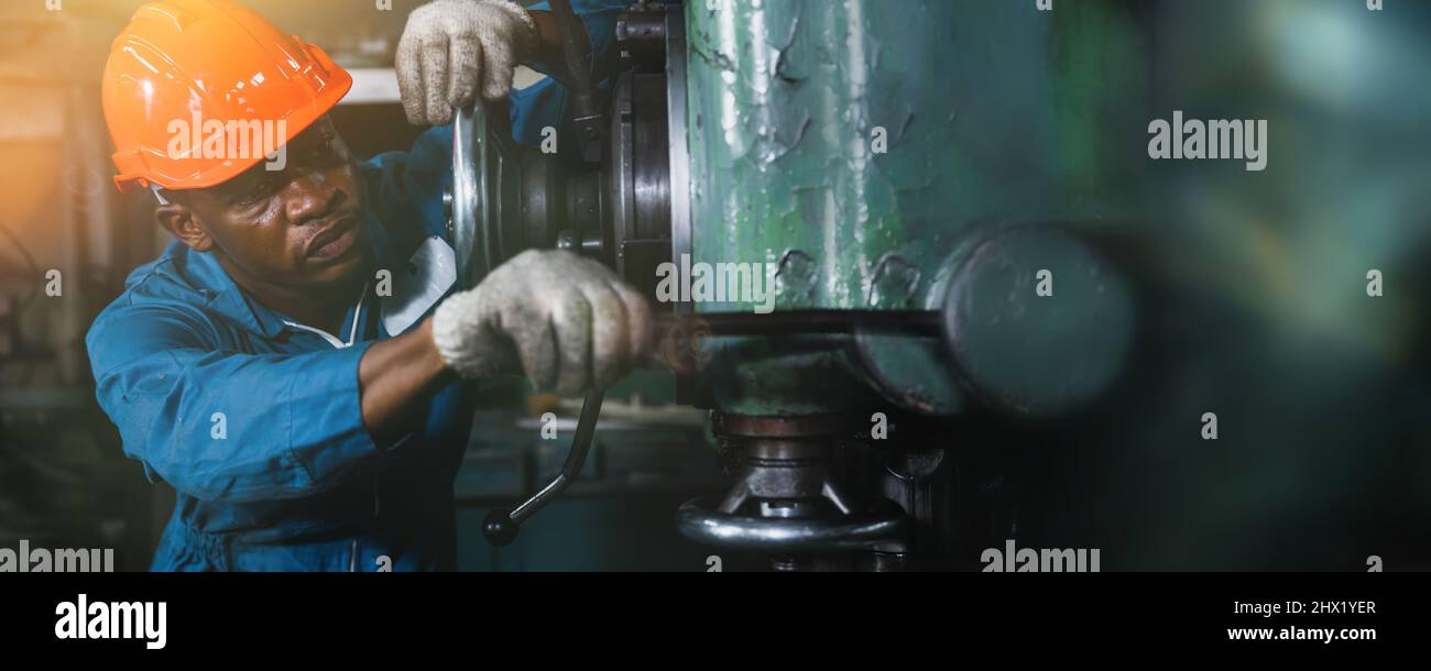 African engineer and worker working and controlling machine in factory ...