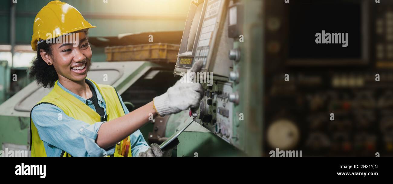 Happy African engineer woman working and checking machine in factory ...