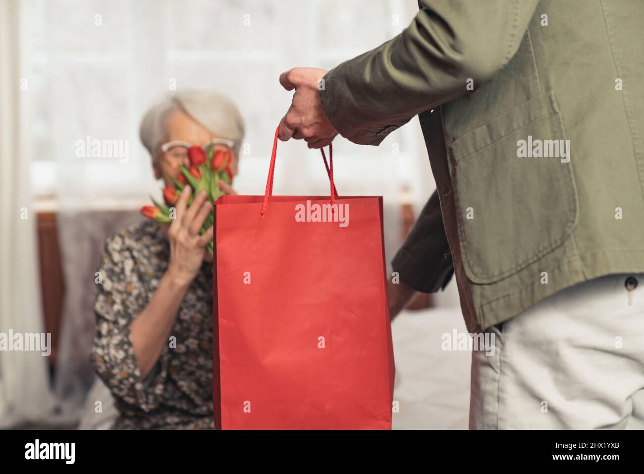 European man giving his mother a present for upcoming Mother's Day ...