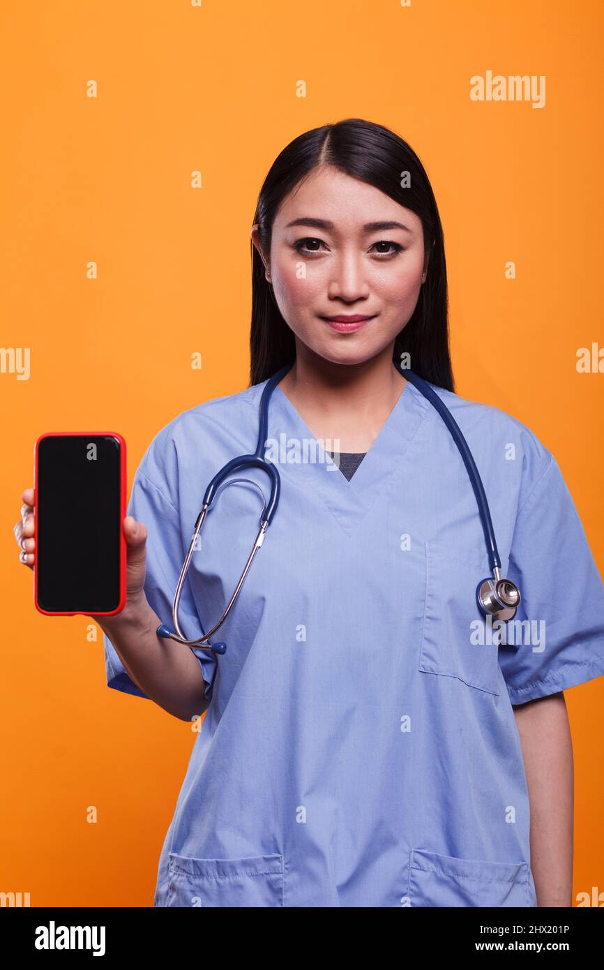 Attractive healthcare clinic nurse wearing stethoscope while showing ...