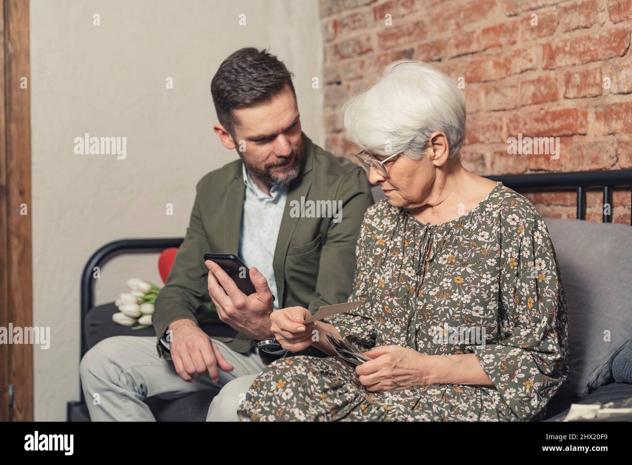 middle-aged caucasian man explaining his elderly grandmother how to use ...