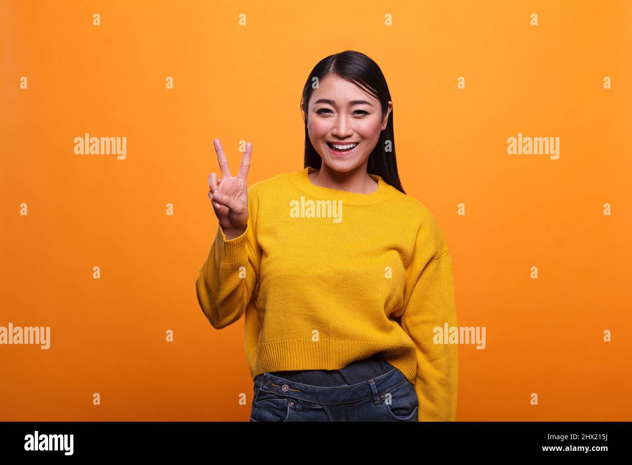 Happy beautiful asian woman giving peace sign while smiling heartily on ...