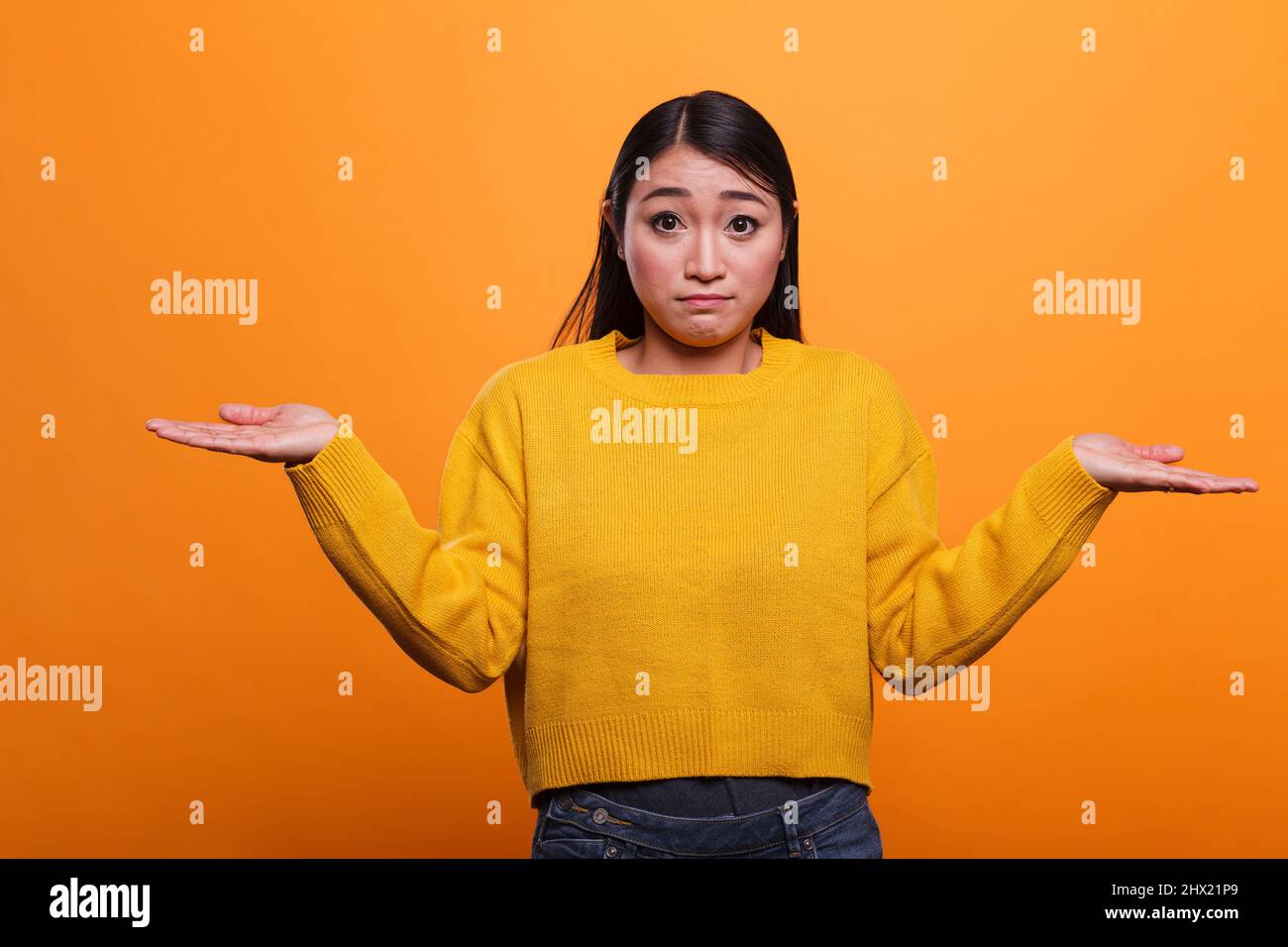 Confused uncertain asian woman shruging unsurely while wearing yellow ...