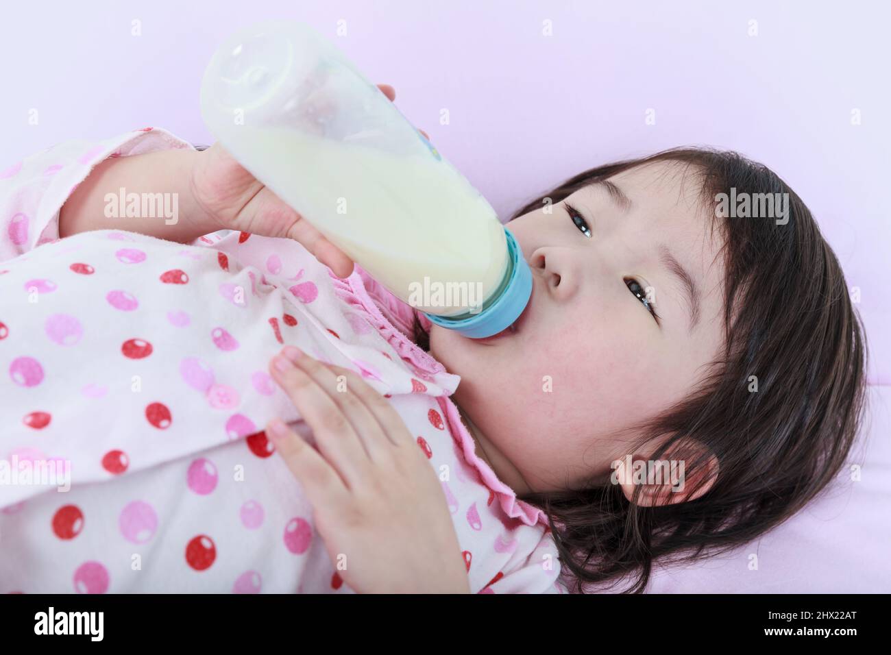 Closeup Cute Asian Girl Sucking Up Milk Bottle In Bed Drinking Milk