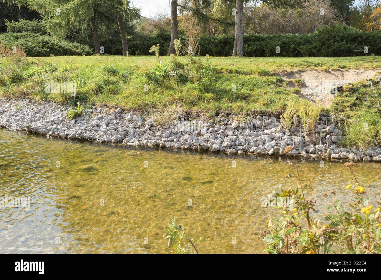Strengthening the banks of the river, mesh and stones. Landscape river ...