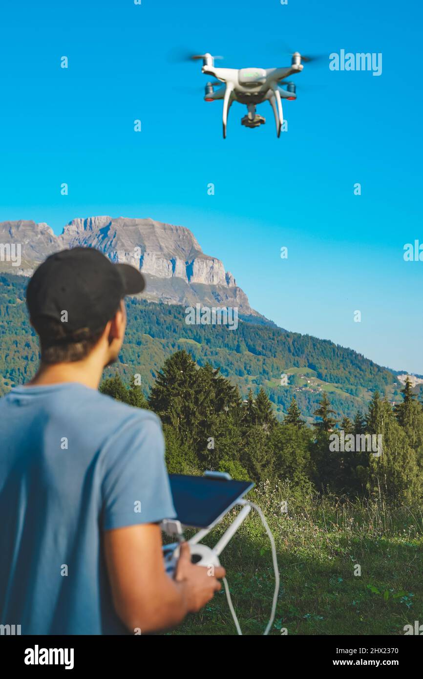 Young man flying drone on amazing mountain landscape. Man operating a ...