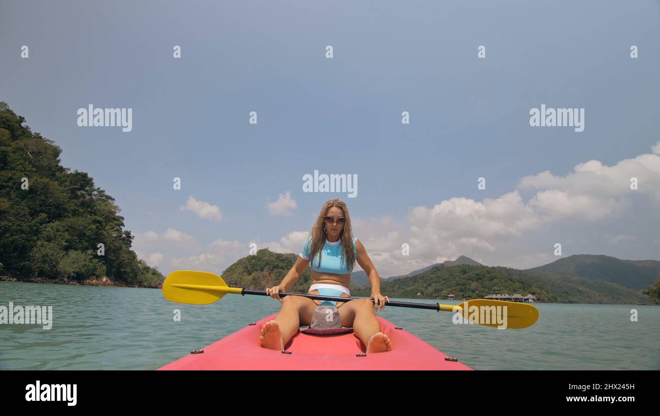 Pretty young blonde woman in stylish swimsuit and sunglasses sits on ...