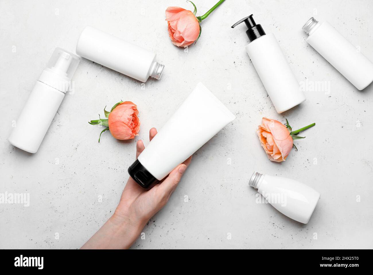 Female hand with different cosmetic products and rose flowers on light ...