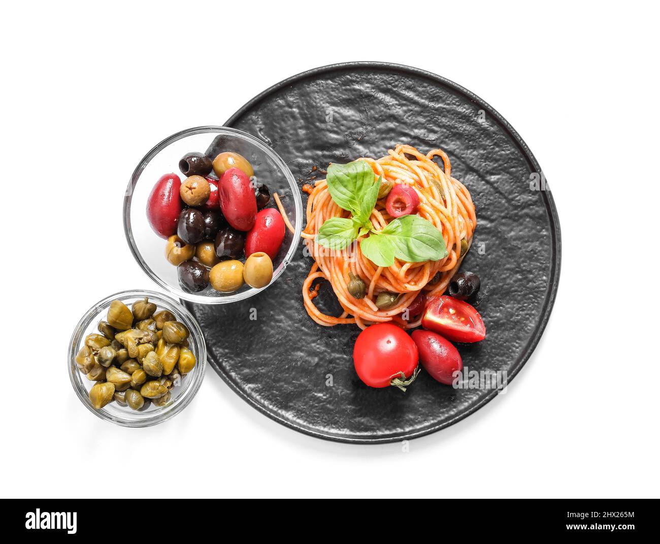 Plate with delicious Pasta Puttanesca and ingredients on white ...