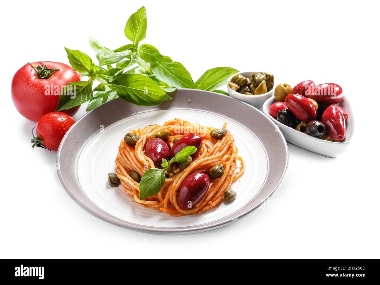 Plate with delicious Pasta Puttanesca, ingredients and basil on white ...
