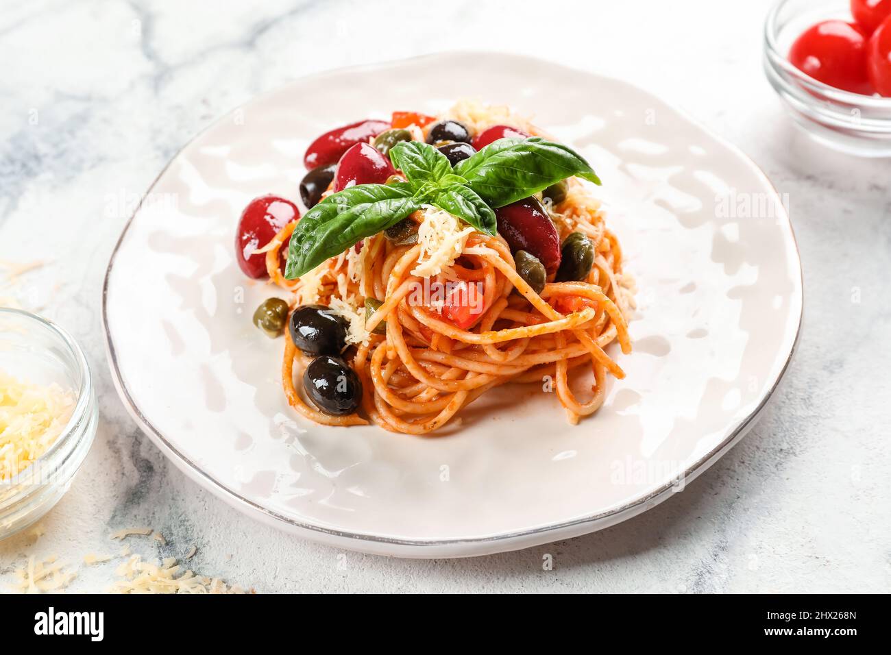 Plate with delicious Pasta Puttanesca and basil on white background ...