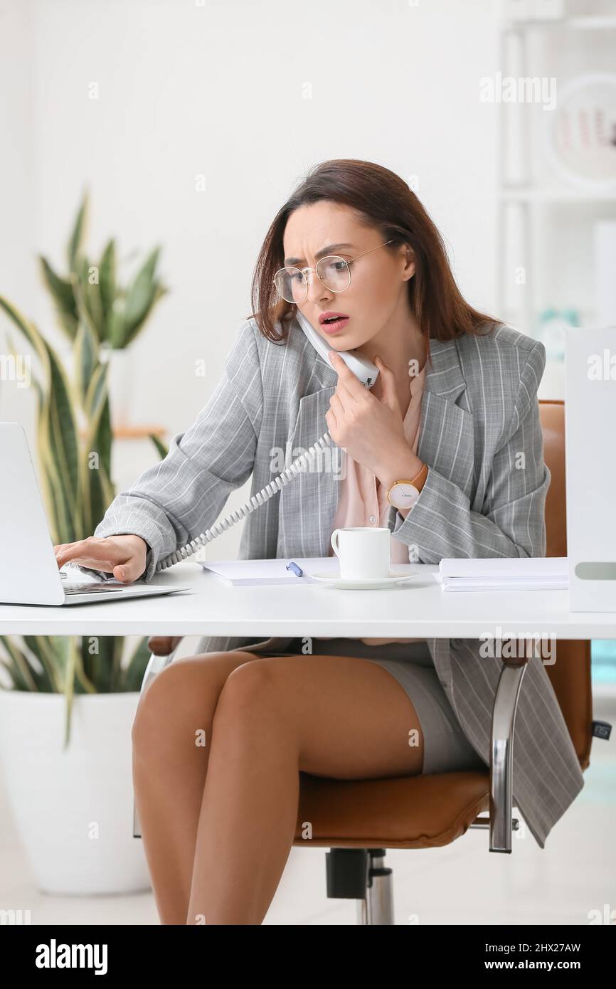 Young worried secretary talking by phone while working in office Stock ...