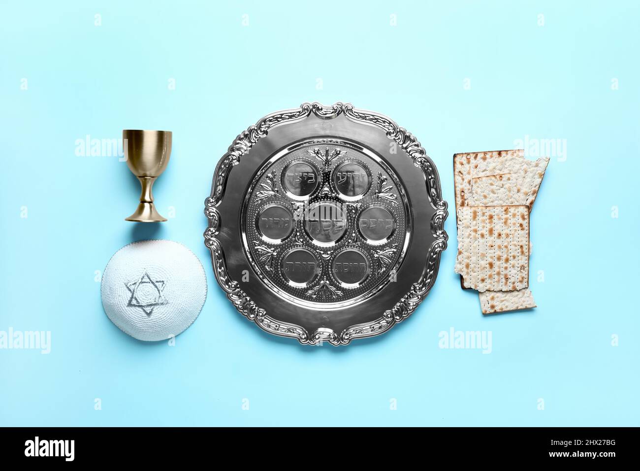 Passover Seder plate, flatbread matza, kippah and cup on blue ...