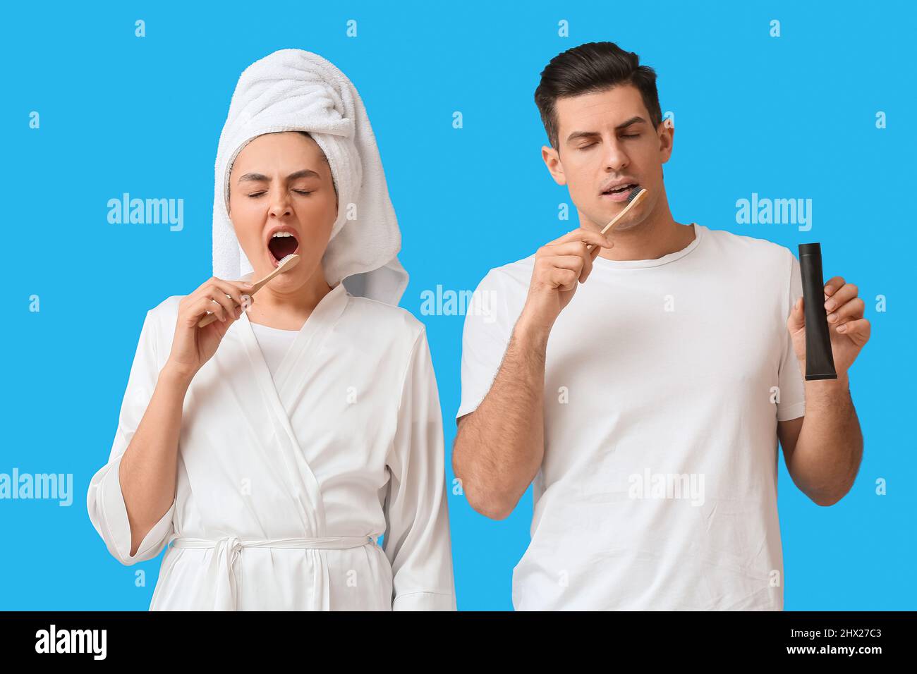 Sleepy young couple brushing teeth with activated charcoal tooth paste ...