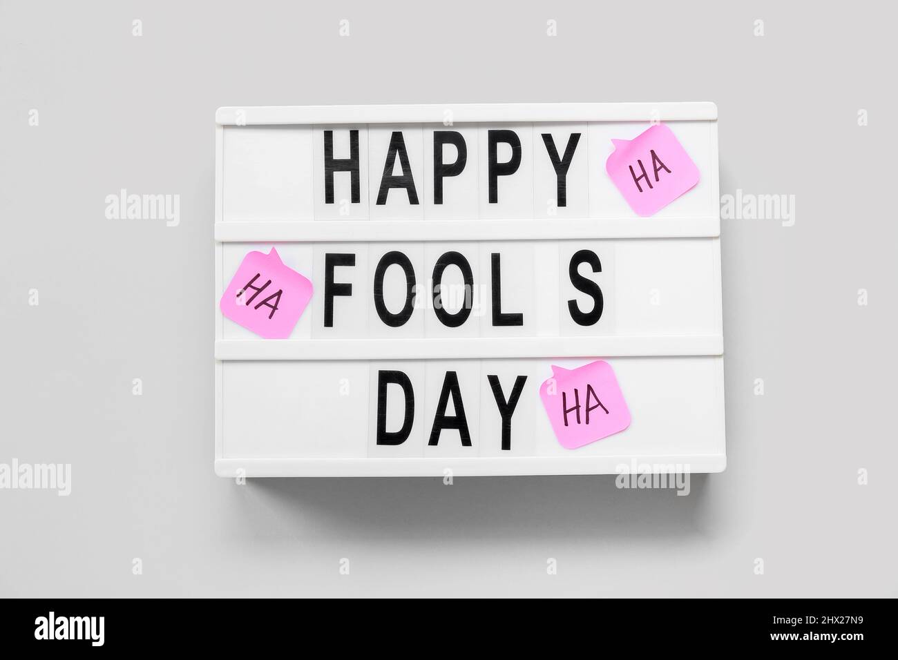 Board with text HAPPY FOOLS DAY and sticky notes on light background ...