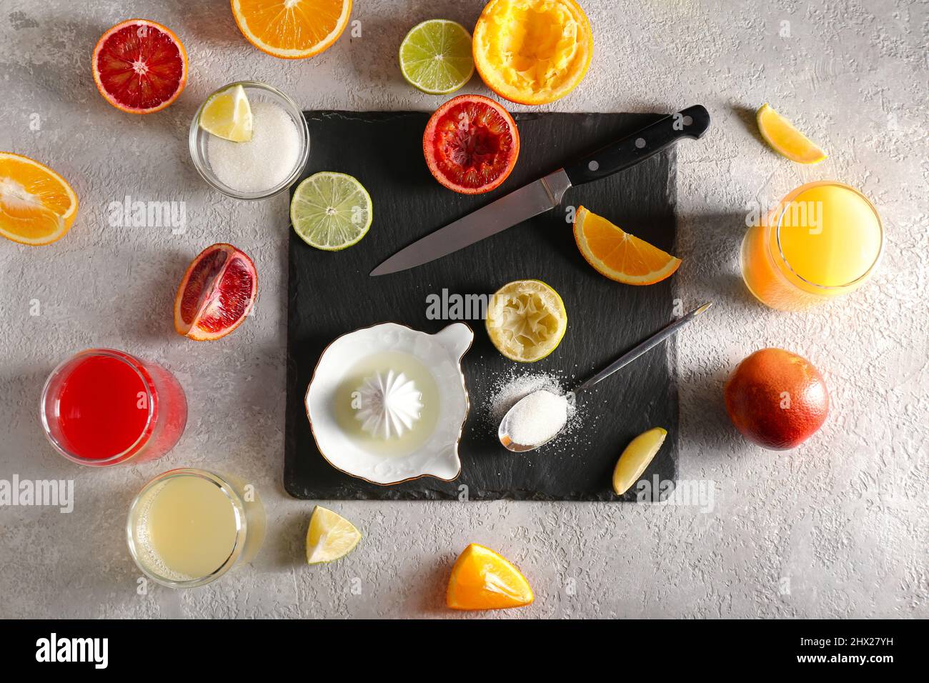 Ceramic juicer, juice, sugar and citrus fruits on grey background Stock ...