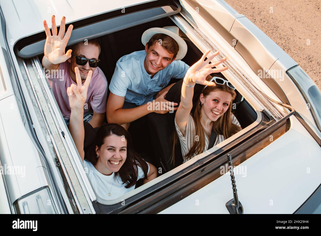 group of friends in car looking up through sunroof. road trip ...