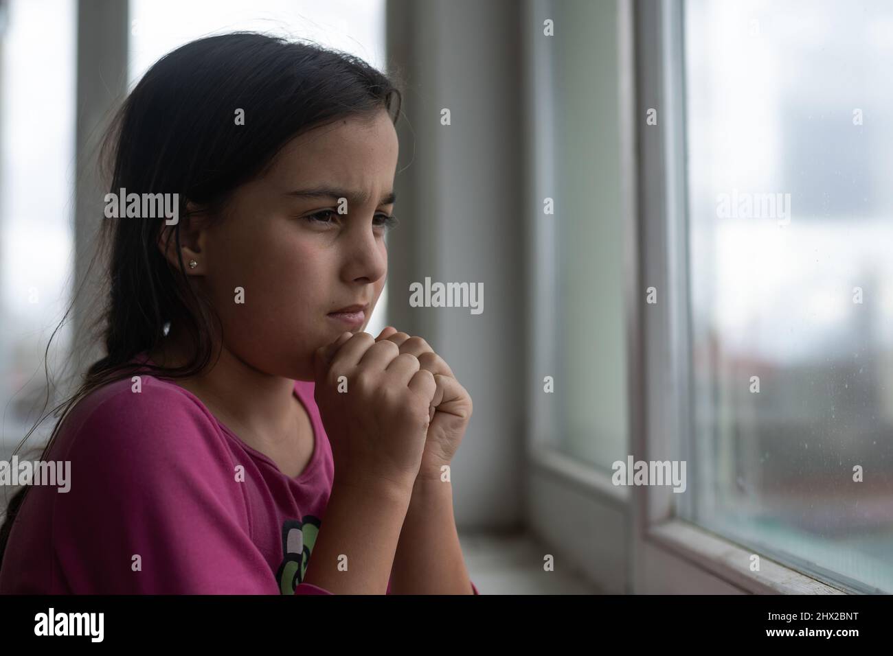 Praying little girl near window Stock Photo - Alamy