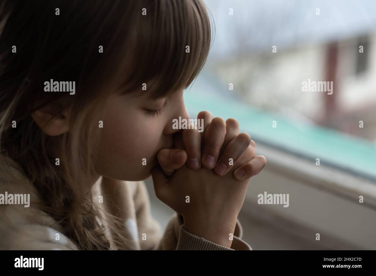 Praying little girl near window Stock Photo - Alamy
