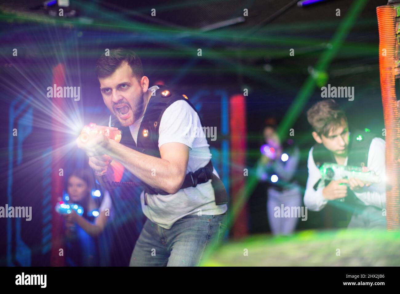 Emotional guy playing laser tag in colorful beams Stock Photo - Alamy