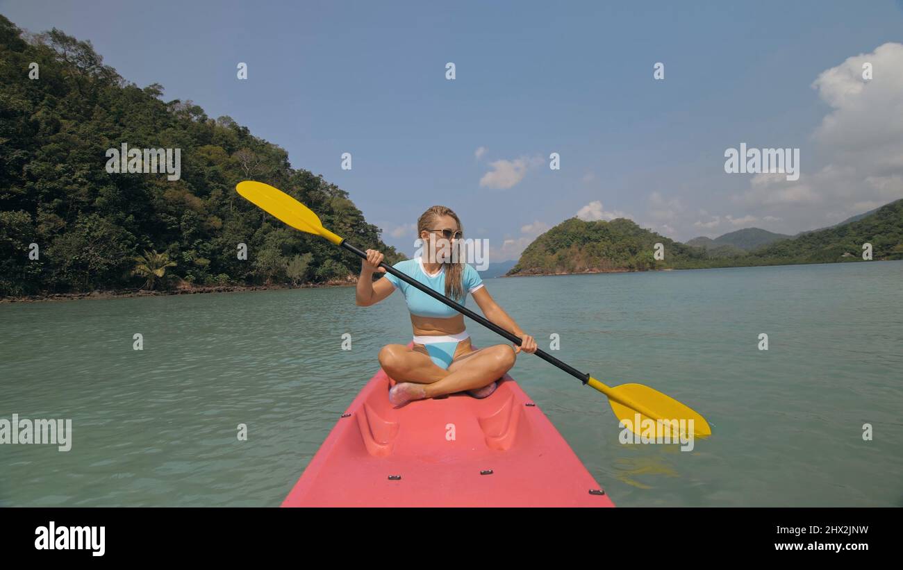 Attractive sportive blonde woman with sunglasses rows pink plastic ...