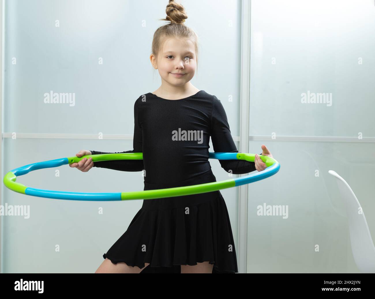 A child spins a hoop at home in the living room. Little girl with a ...