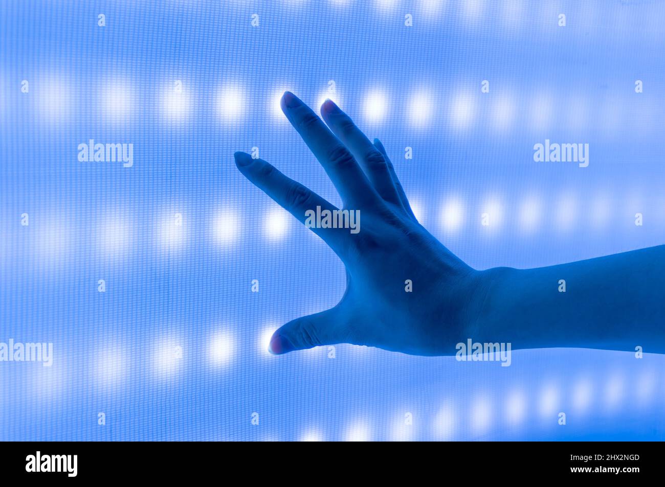 hand and led touch screen blue light science and technology background ...