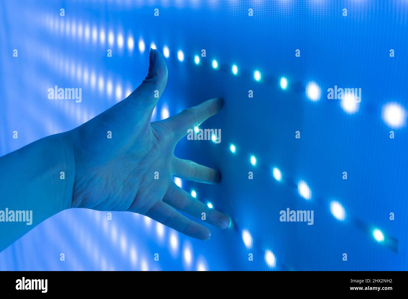 hand and led touch screen blue light science and technology background ...