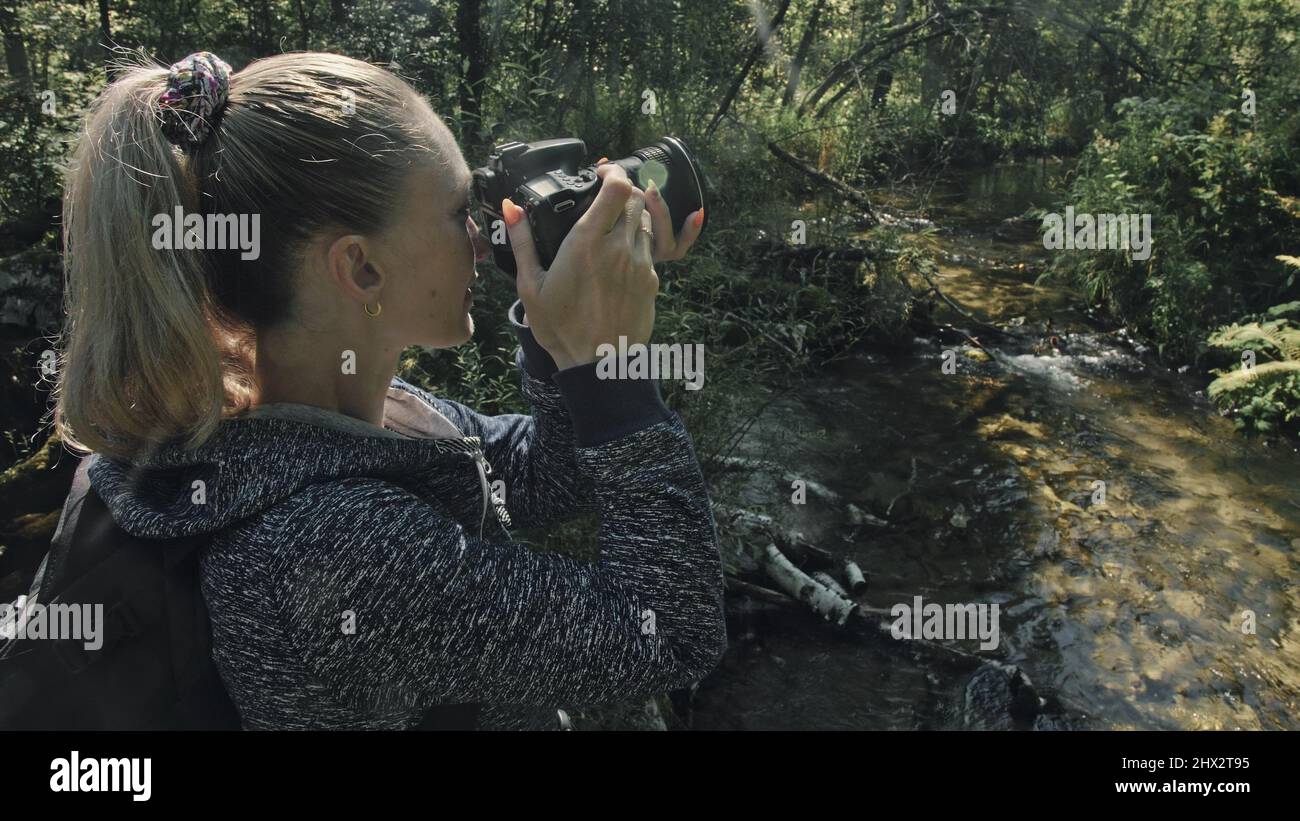 Traveler photographing scenic view in forest river. Wood bridge fallen ...
