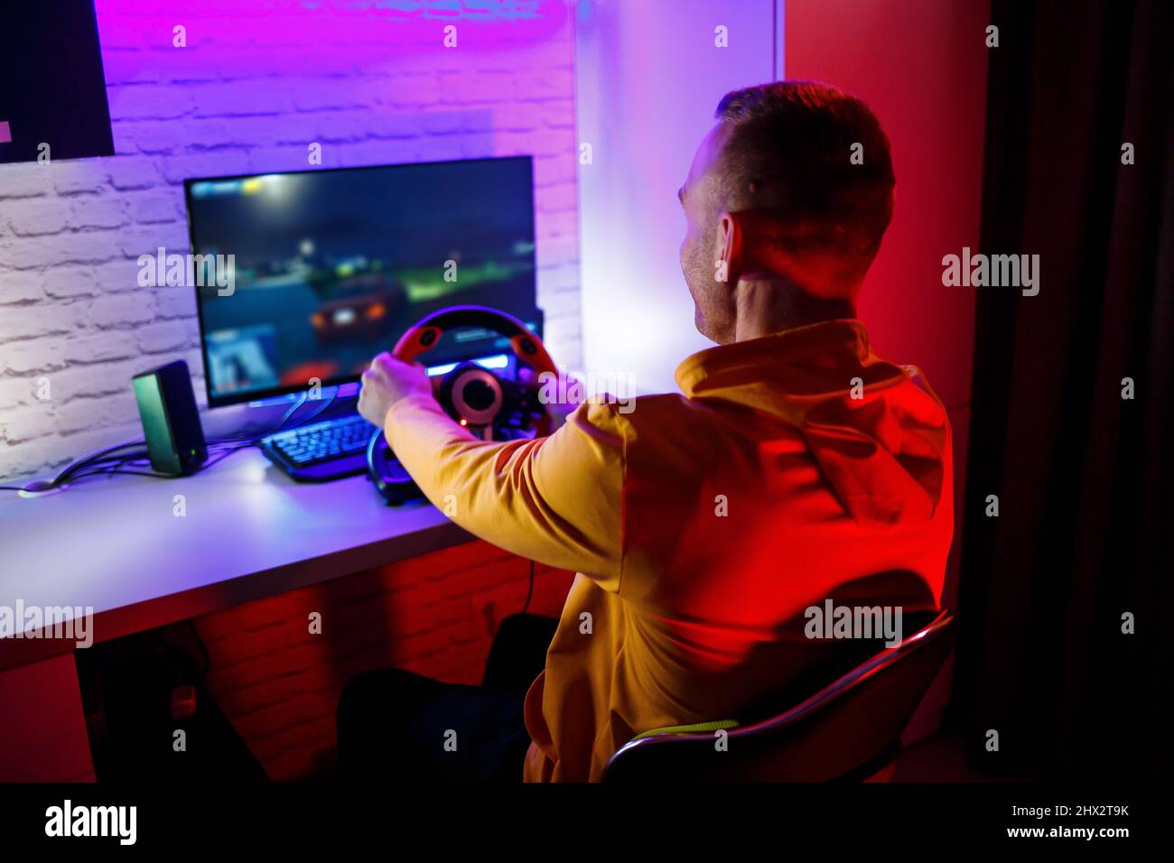 Male gamer playing racing games on the computer. He uses the steering ...