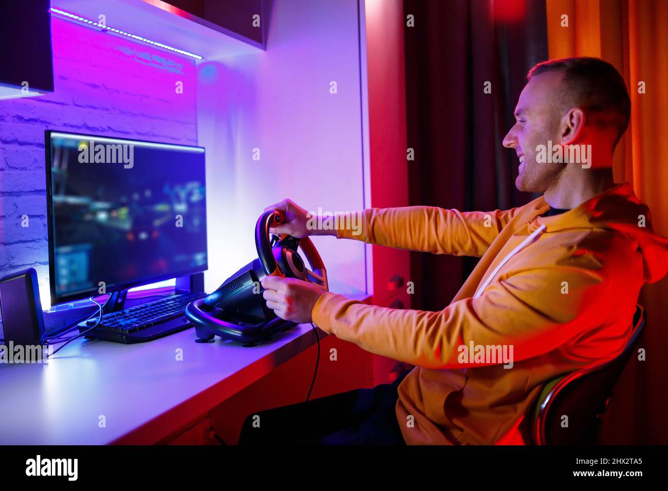 Male gamer playing racing games on the computer. He uses the steering ...