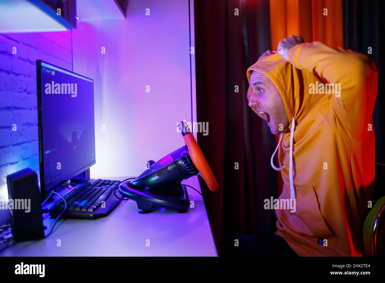 Male gamer playing racing games on the computer. He uses the steering ...