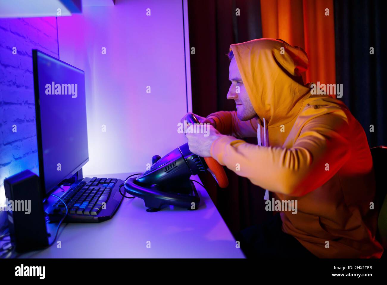 Male gamer playing racing games on the computer. He uses the steering ...