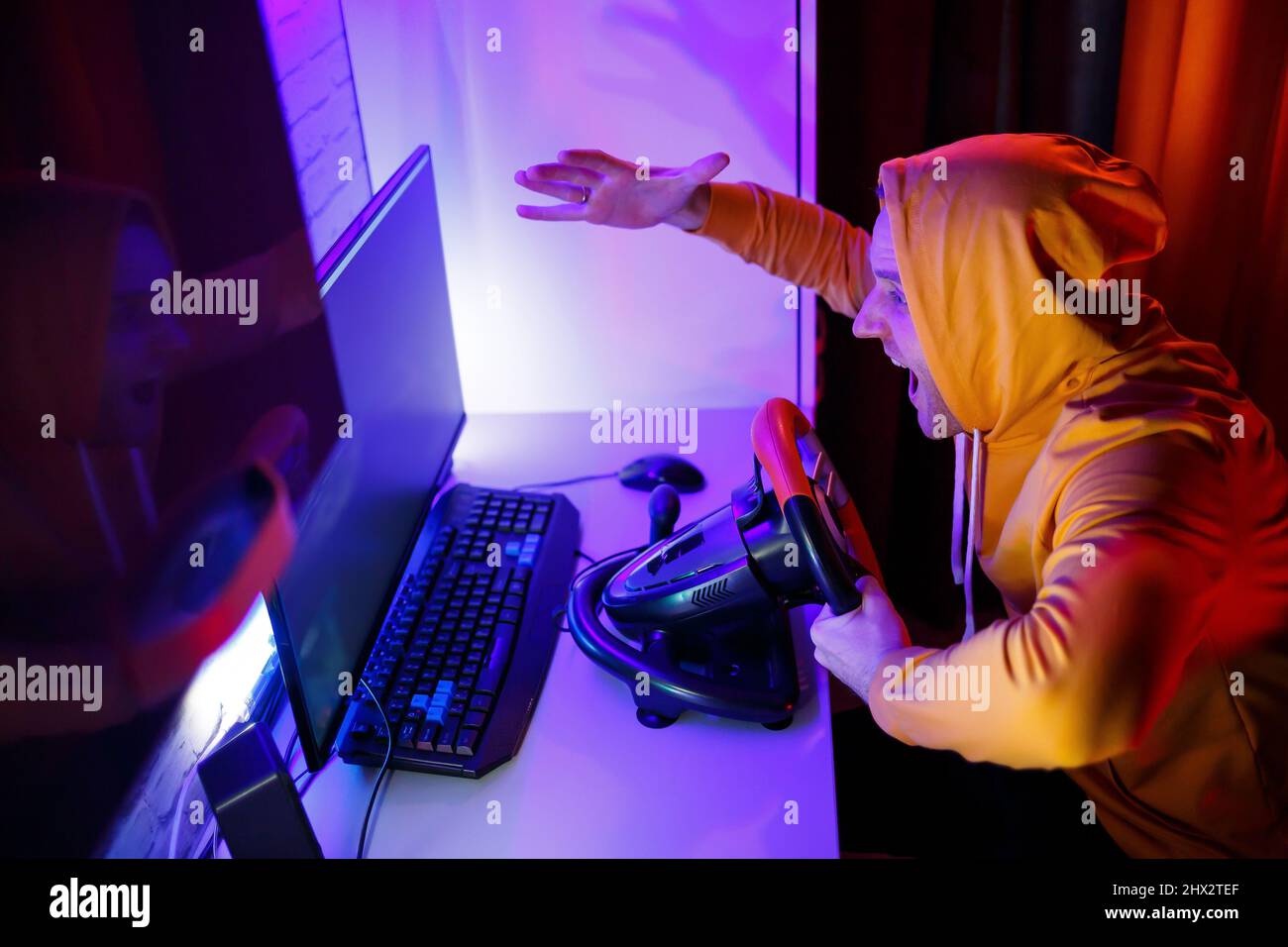 Male gamer playing racing games on the computer. He uses the steering ...