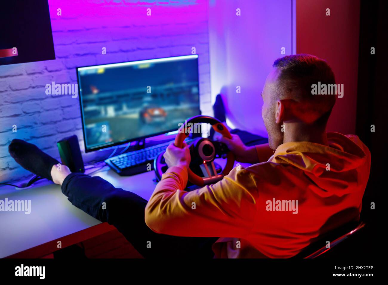 Male gamer playing racing games on the computer. He uses the steering ...