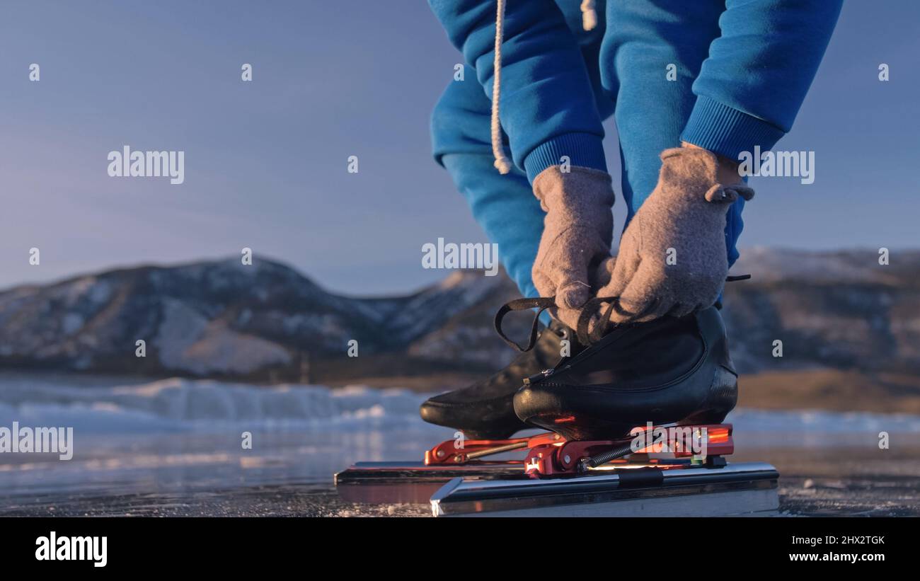 The child train on ice speed skating. Athlete puts on skates. The girl ...
