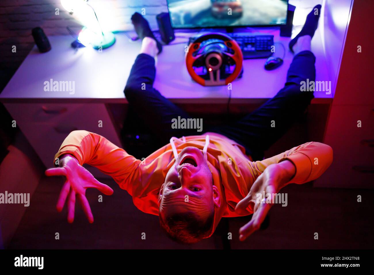 Male gamer playing racing games on the computer. He uses the steering ...