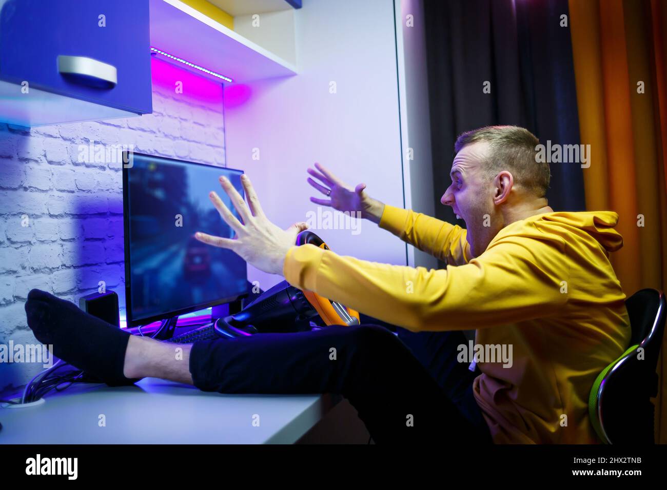 Male gamer playing racing games on the computer. He uses the steering ...