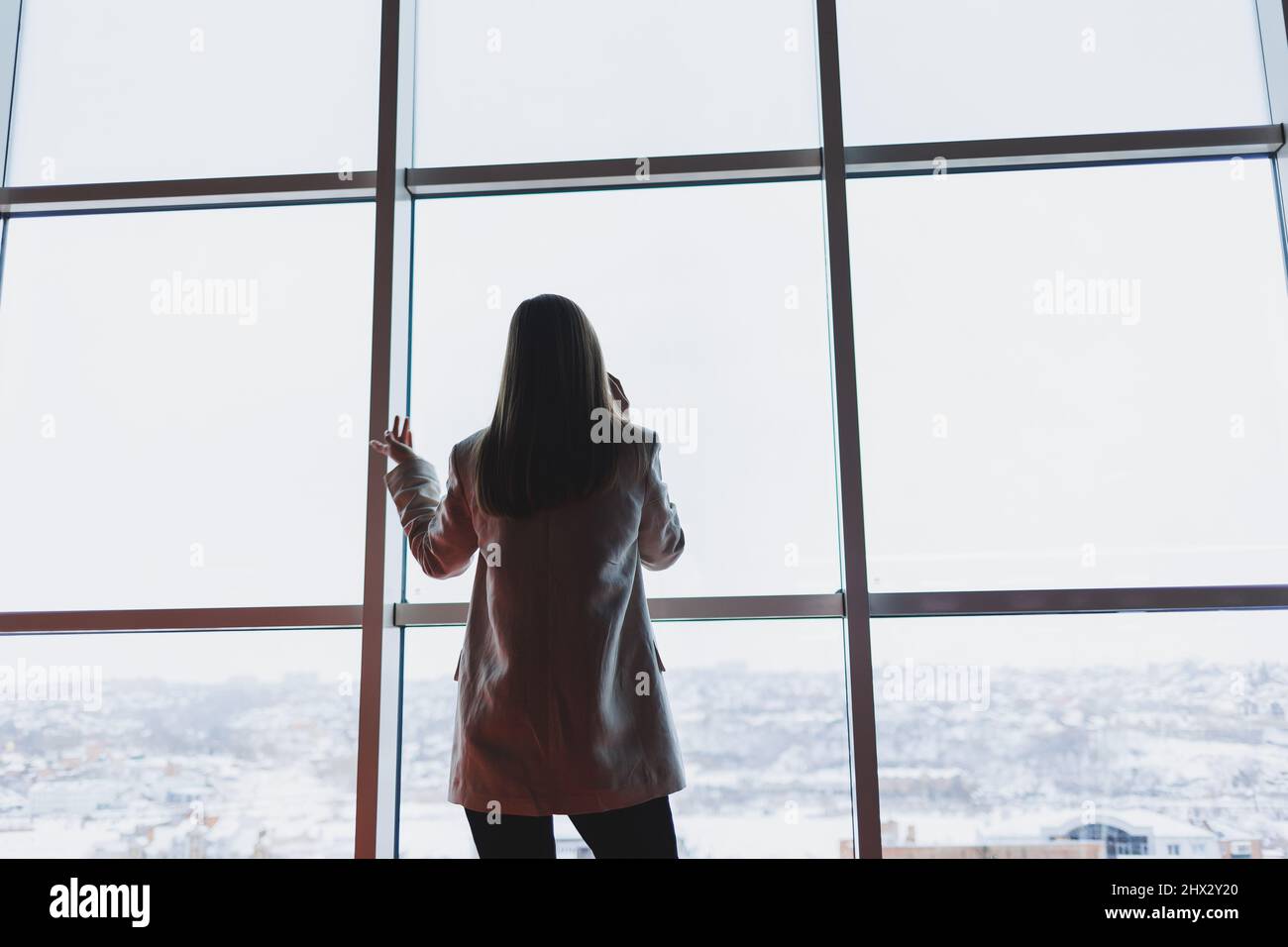 Successful business woman standing looking out the window enjoying the ...