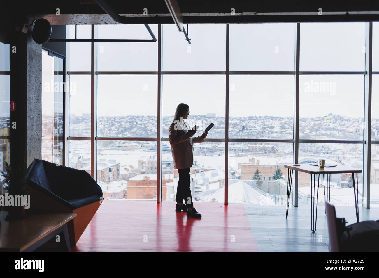 Successful business woman standing looking out the window enjoying the ...