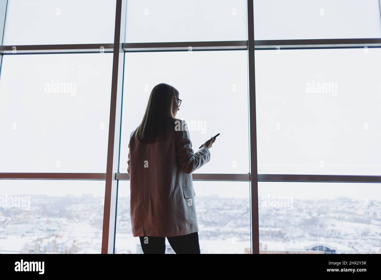 Successful business woman standing looking out the window enjoying the ...