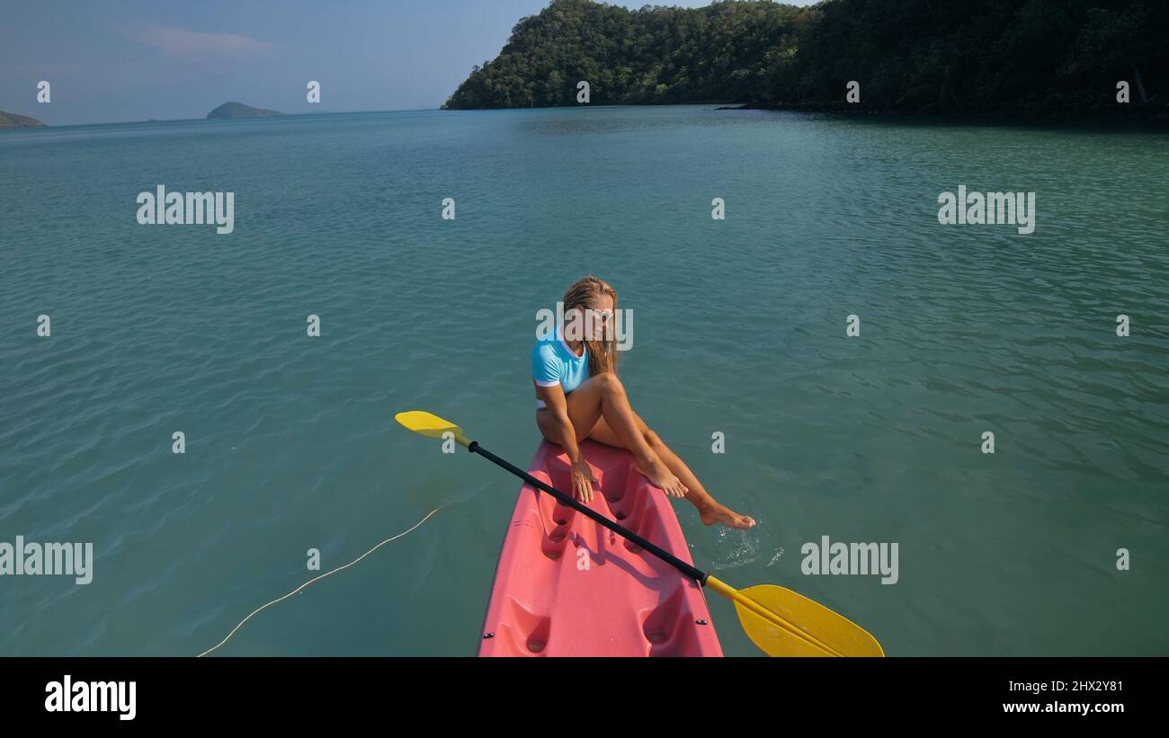 Pretty sportive blonde lady in stylish swimsuit sails on pink plastic ...